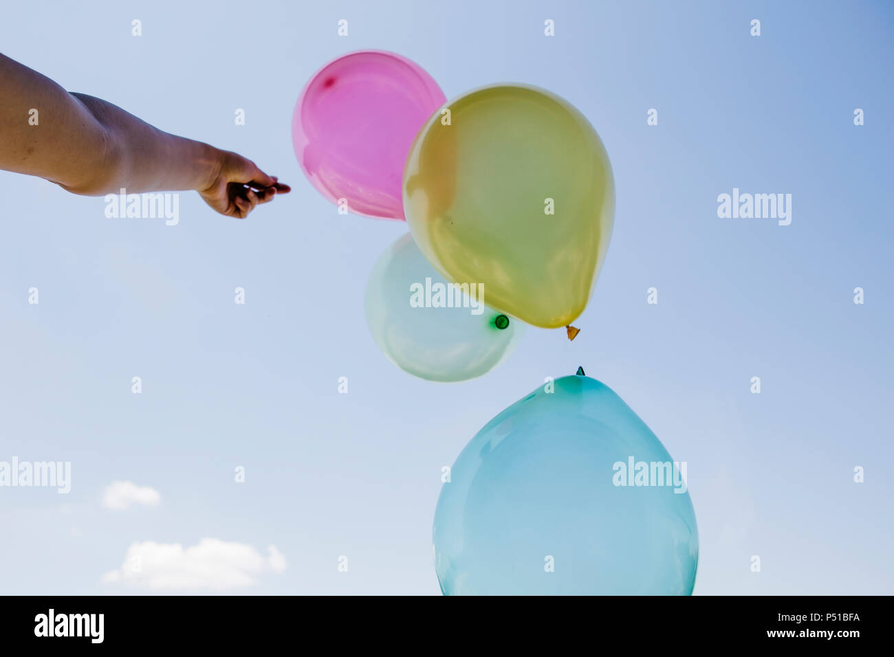 Lots of colorful balloons in the hand against blue sky Stock Photo - Alamy