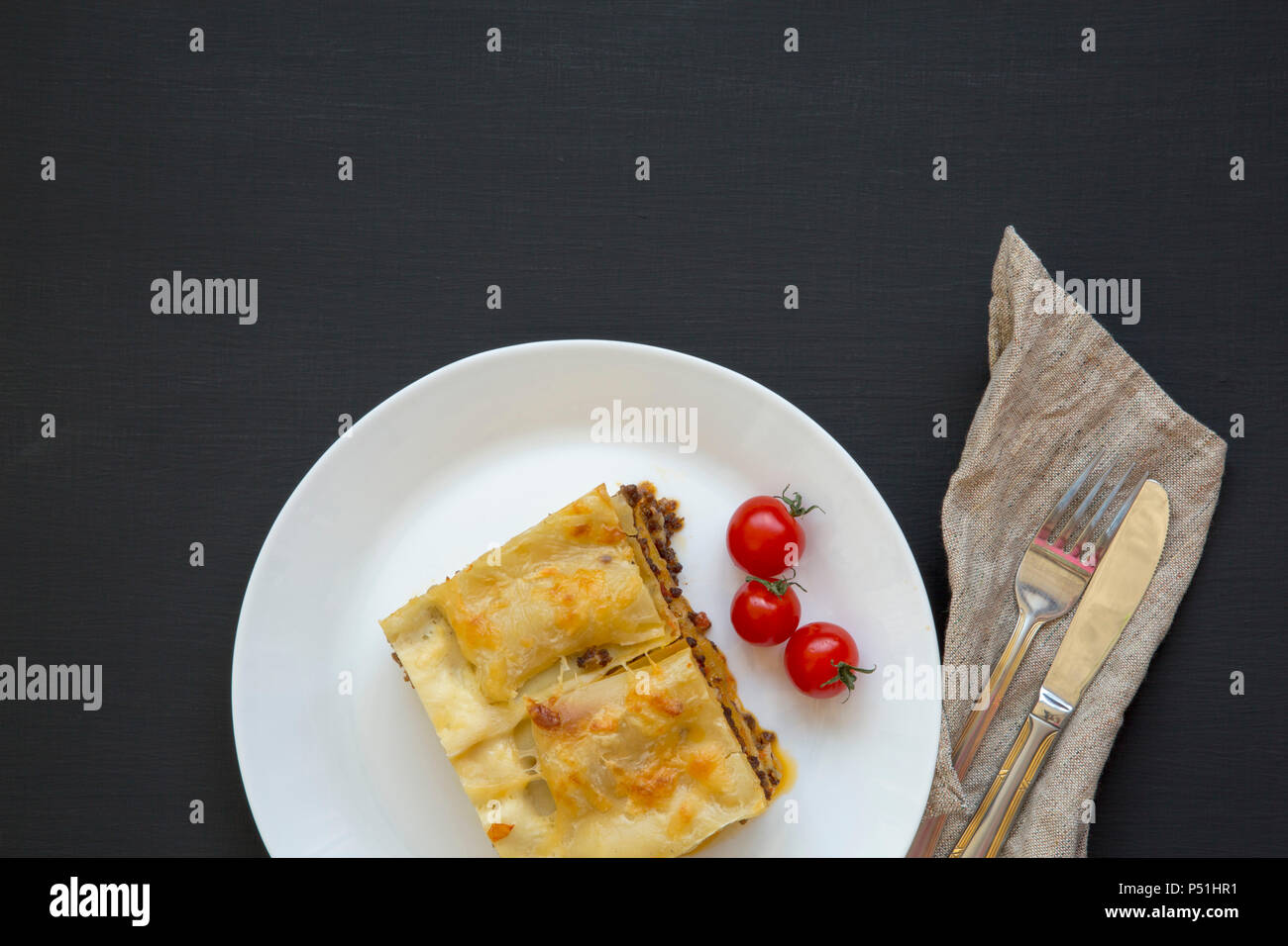 Traditional beef lasagne on a white round plate on black background ...
