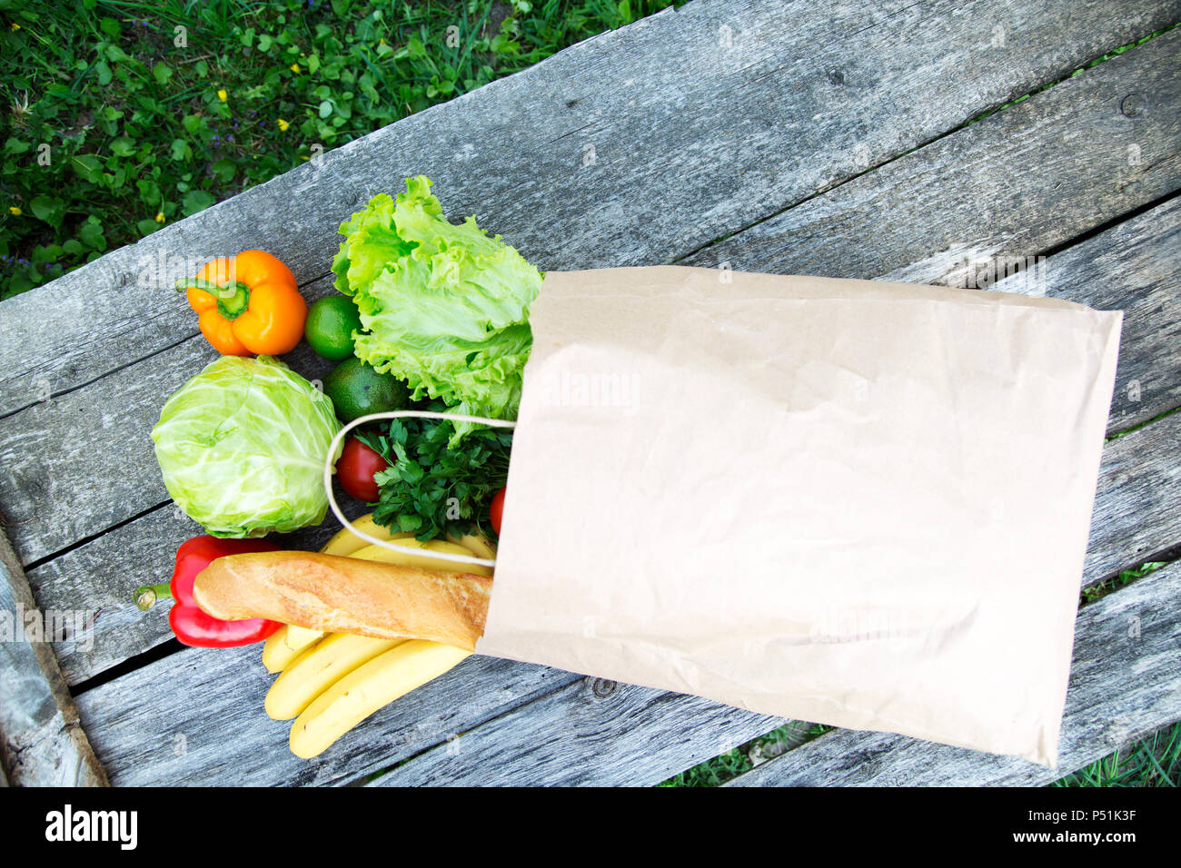 A full paper bag of healthy products stands on wooden table. Top view ...