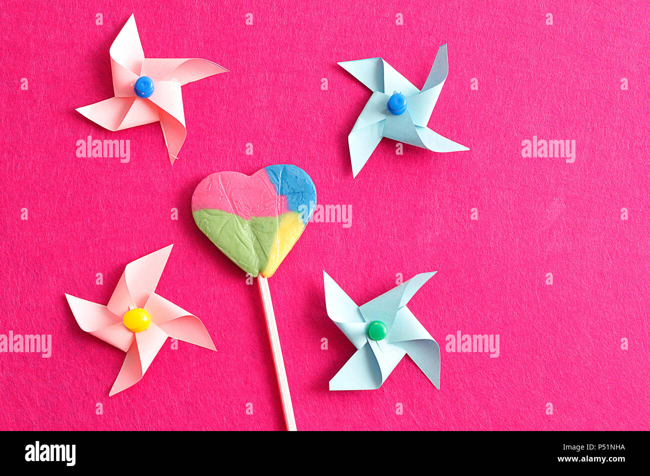A colorful heart shape lollipop displayed with colorful pinwheels on a ...