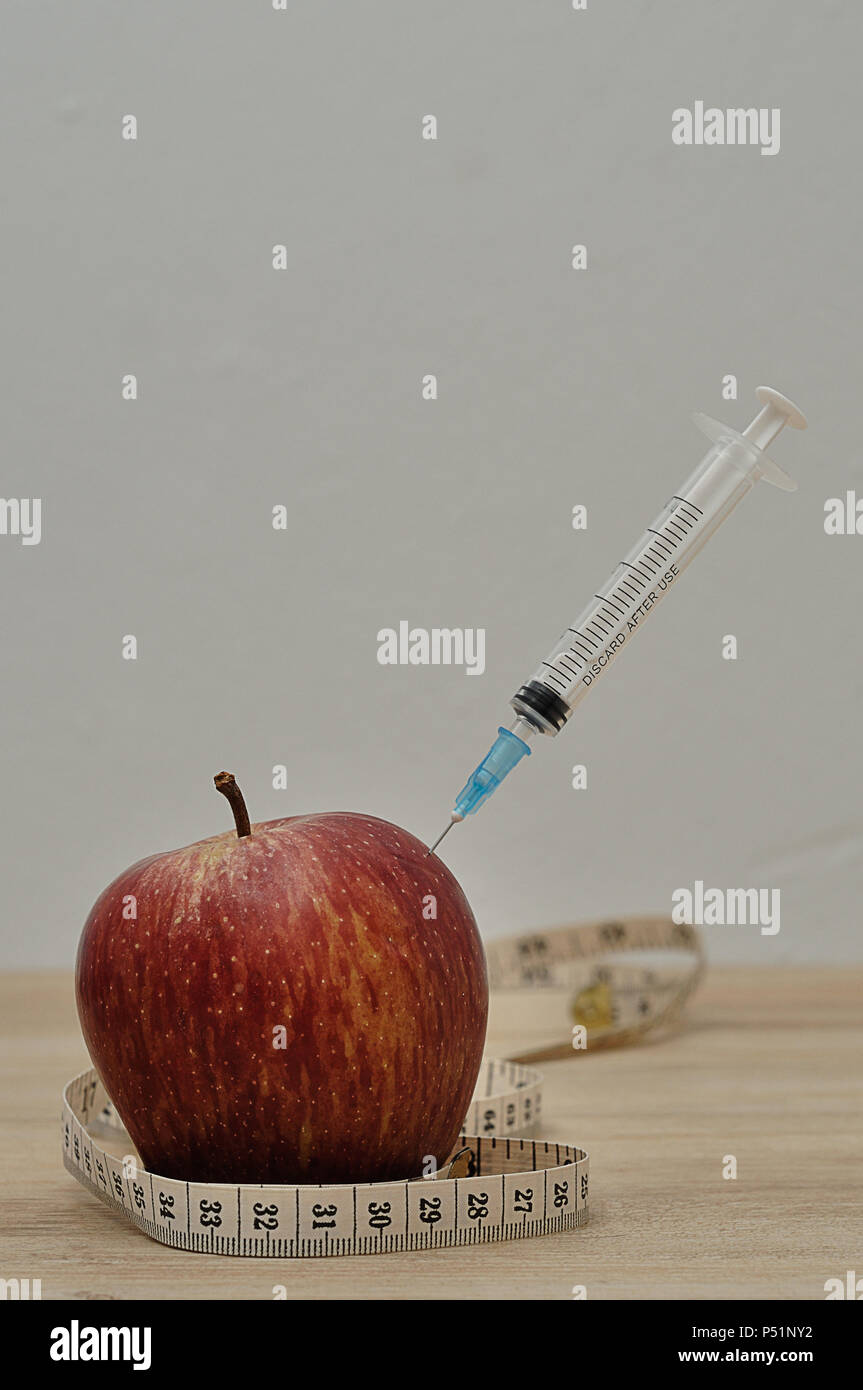 An injection needle stuck into an apple with a measuring tape Stock ...