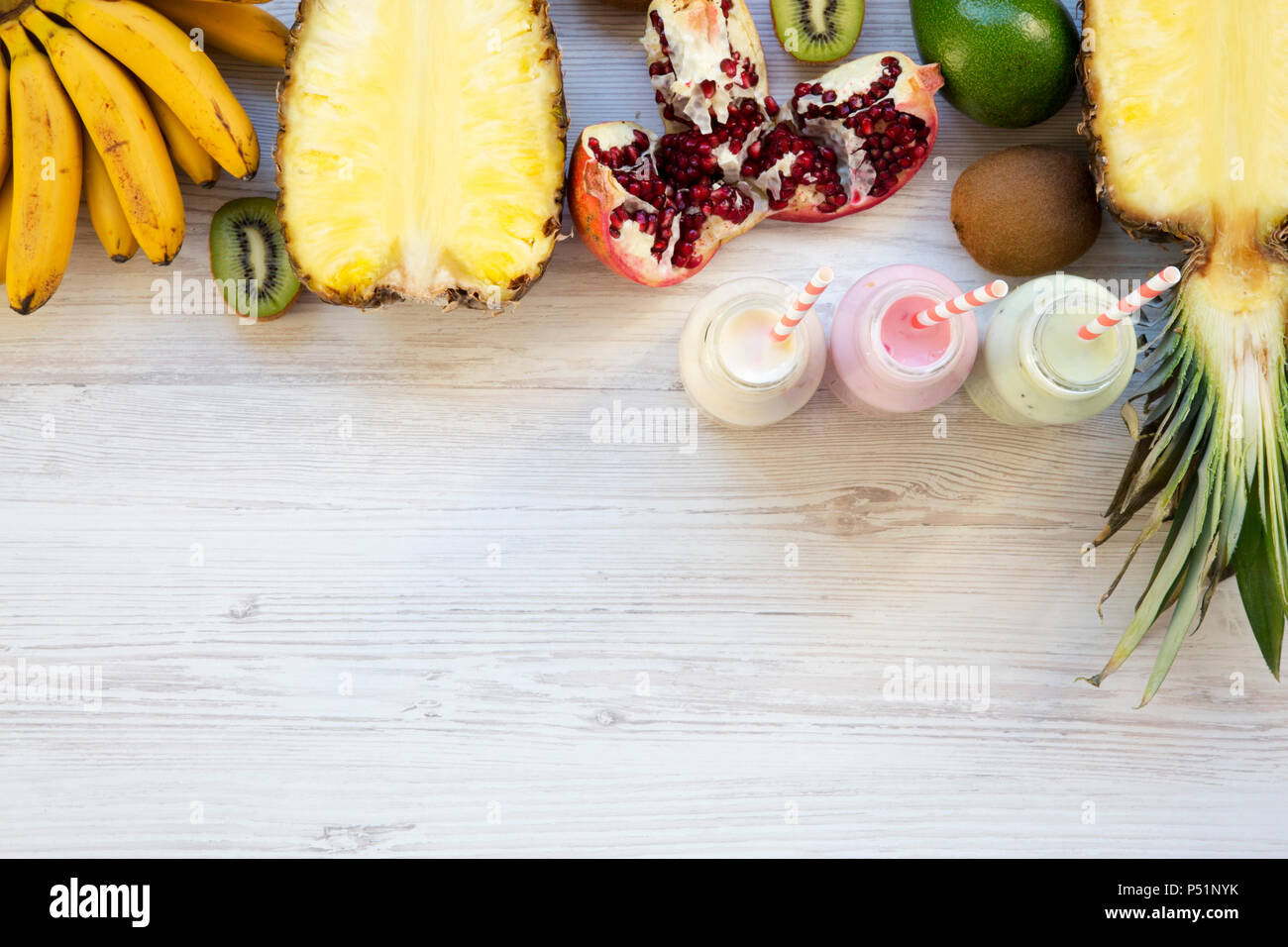Fruit smoothies in glass bottles with ingredients on white wooden table ...