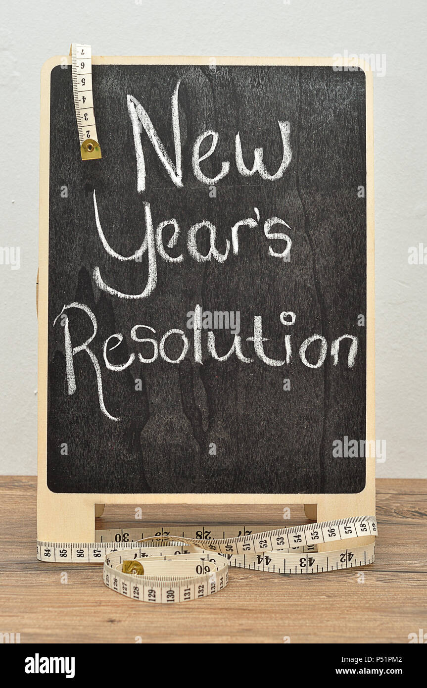 A black board with the words new years resolution and a measuring tape ...