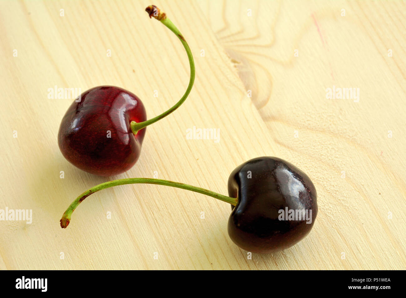 Two dark sweet cherries on pine background in horizontal format and ...