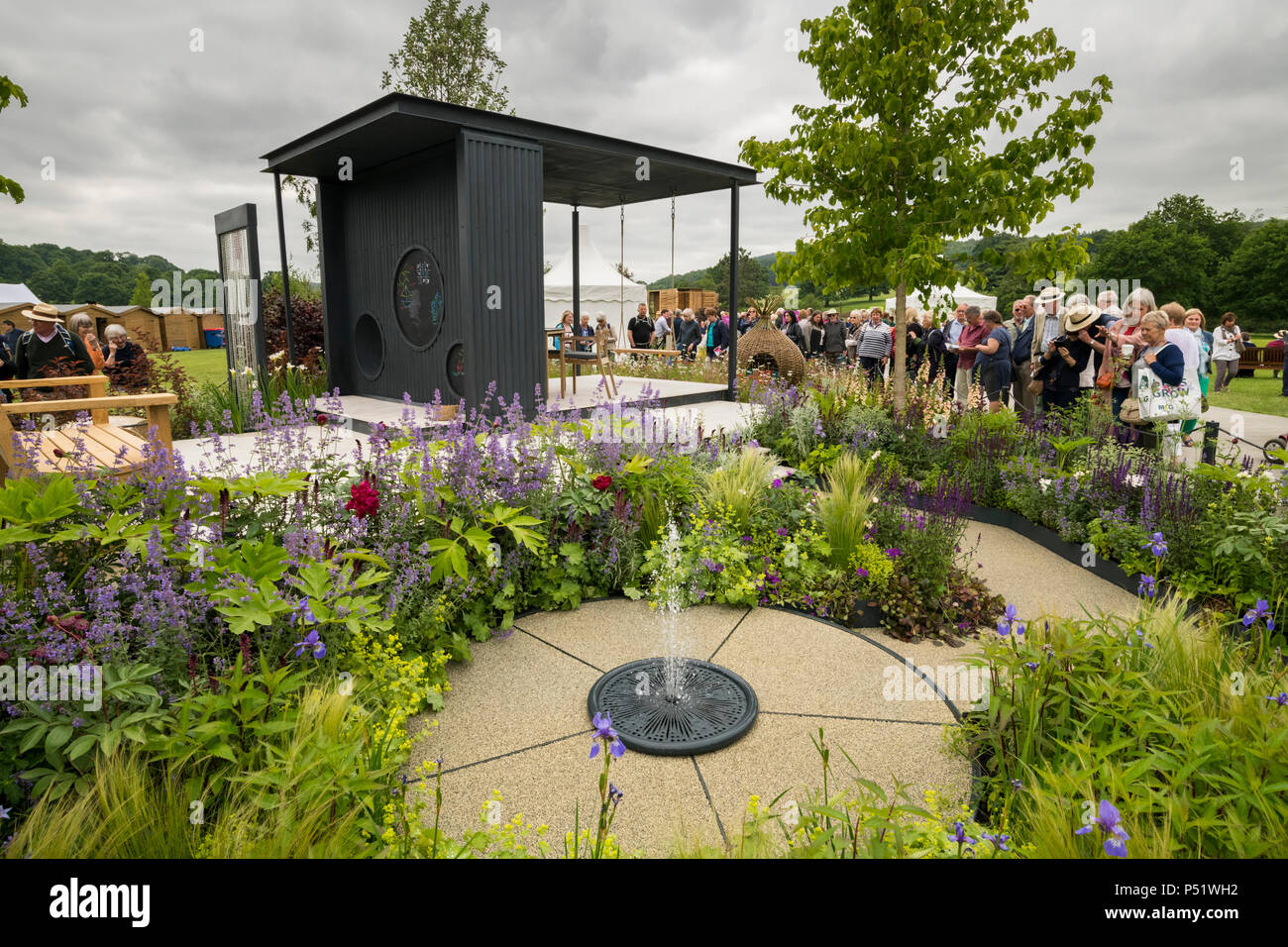 People viewing seating in pavillion, water feature & flowering plants ...