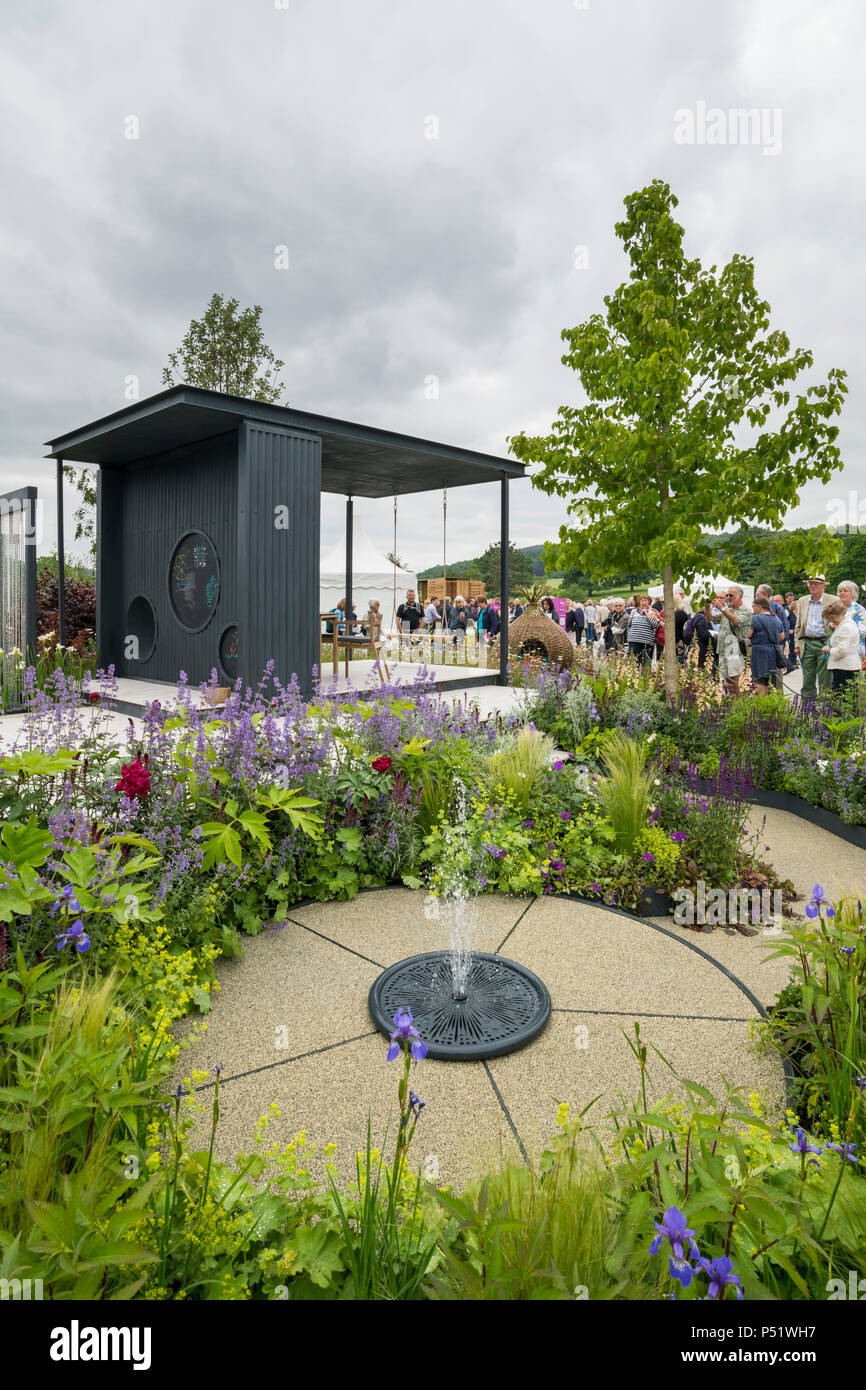 People viewing seating in pavillion, water feature & flowering plants ...