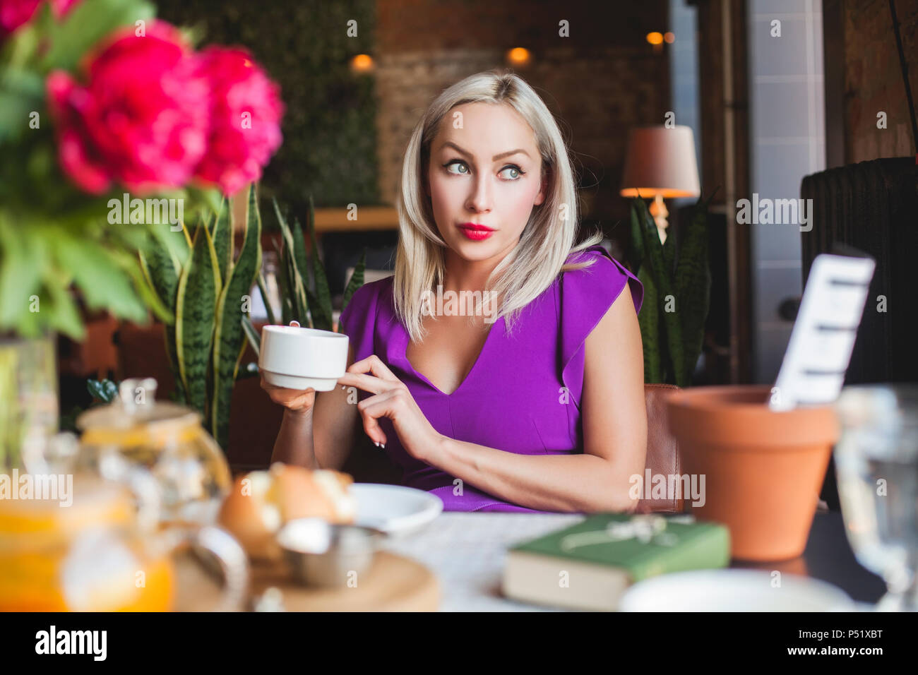Pretty Blonde Woman sitting in Restaurant Stock Photo - Alamy