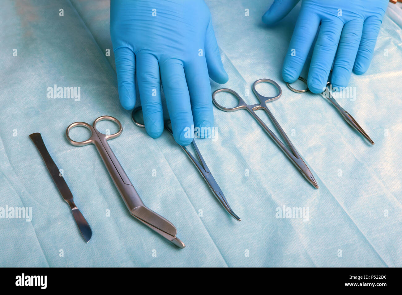 Detail shot of sterilized surgery instruments with a hand grabbing a ...