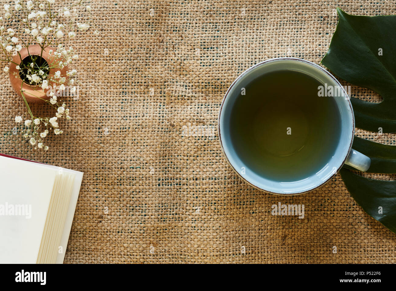 drinking a cup of tea and reading a book on raw fabric modern table ...
