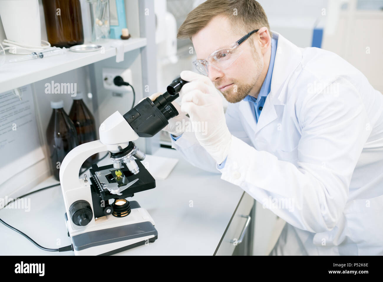 Male microbiologist studying food fibers under microscope Stock Photo ...