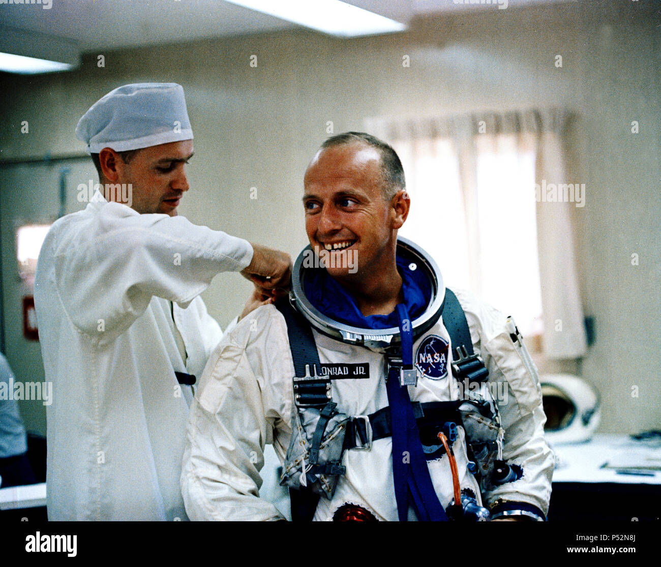 Astronaut Charles Conrad Jr. receives assistance with his pressure suit ...