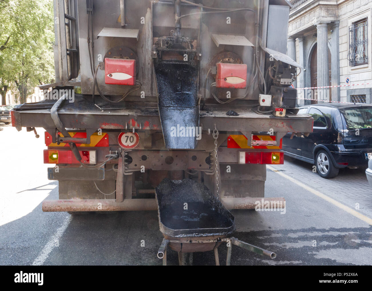 pouring tar from the truck to a wheelbarrow for the repair of road ...