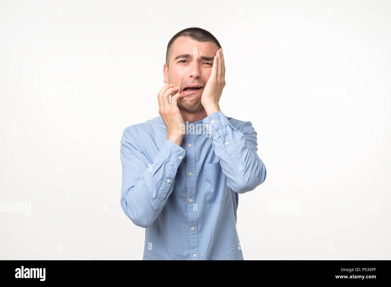 Despaired spanish man in blue shirt is crying. He lost his job or break ...