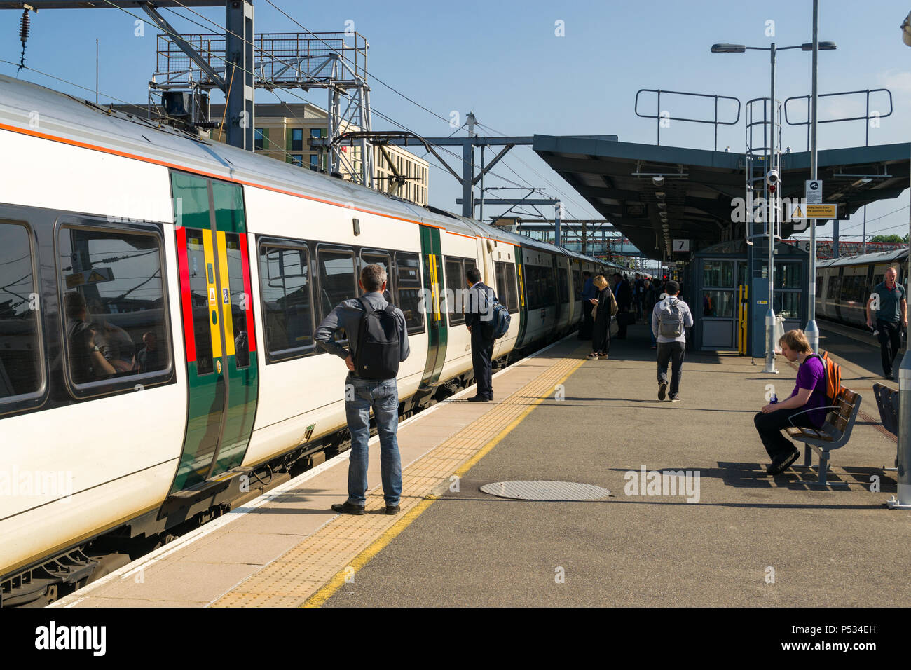 Passengers wait on a platform to board a train from Cambridge train ...