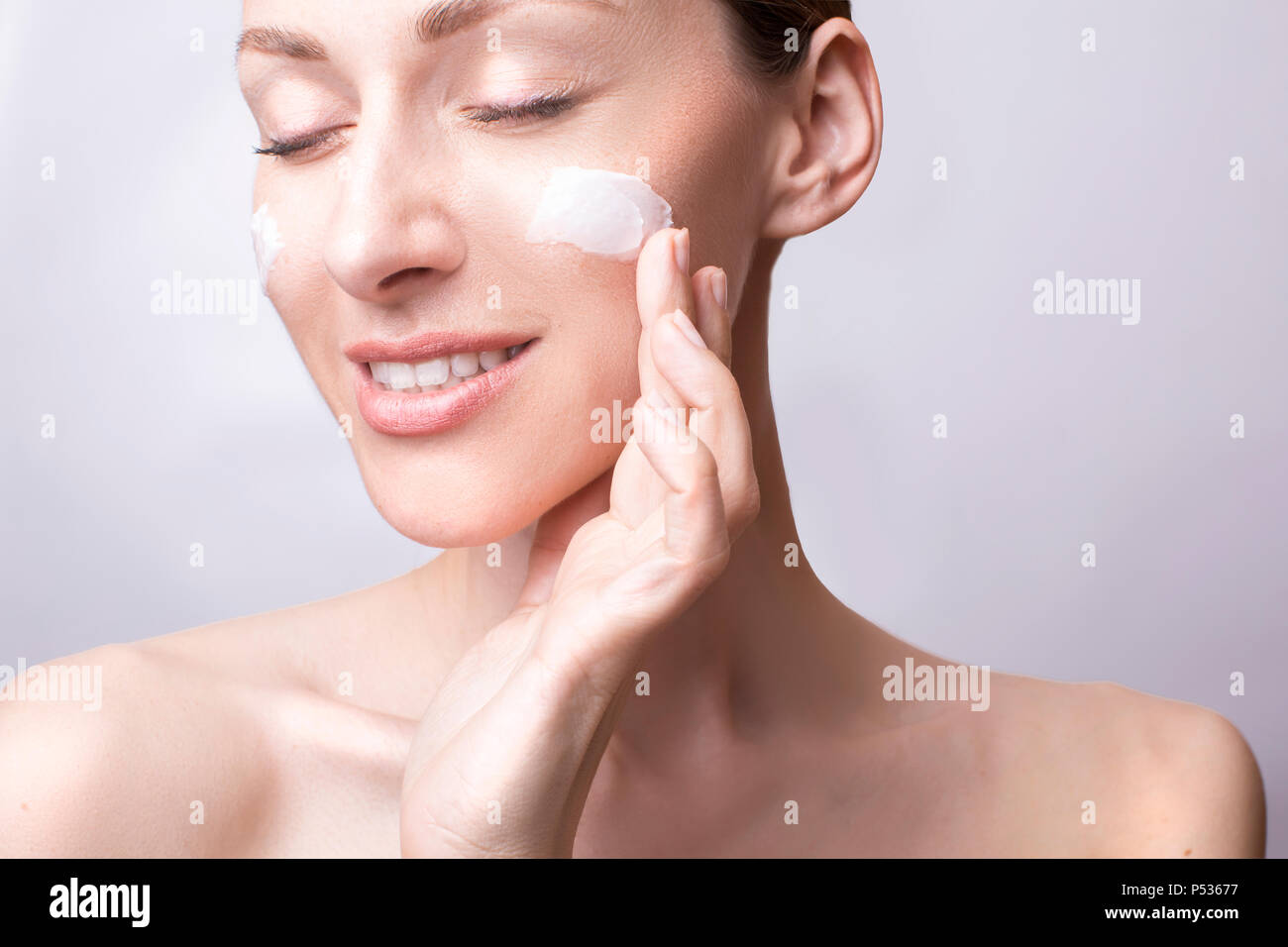 Laughing girl applying moisturizing cream on her face. Photo of young ...