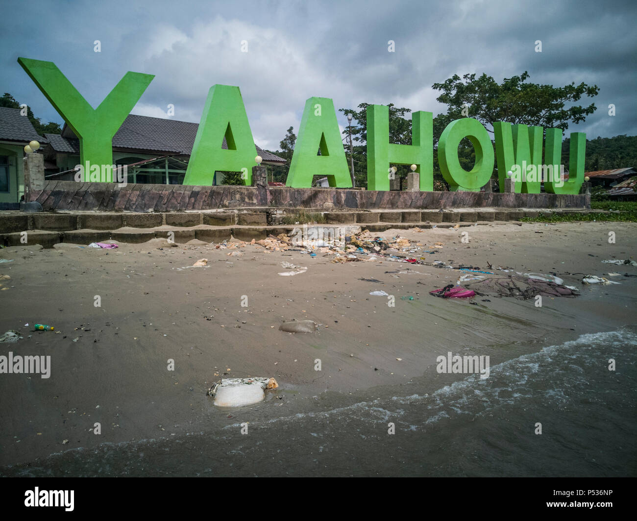 Yaahowu (welcome) sign on beach covered in plastic trash at Gunung ...