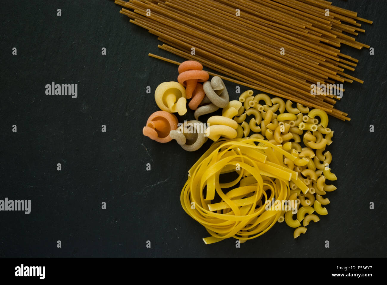 assortment of variety of italian uncooked pasta flat lay on a black ...