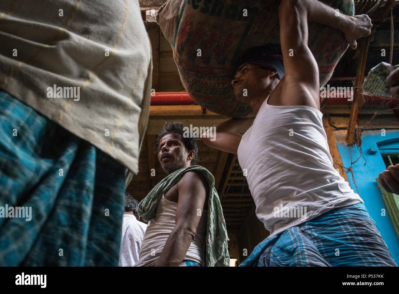 A man hauling a heavy load of goods in Koley Market, Kolkata, India ...