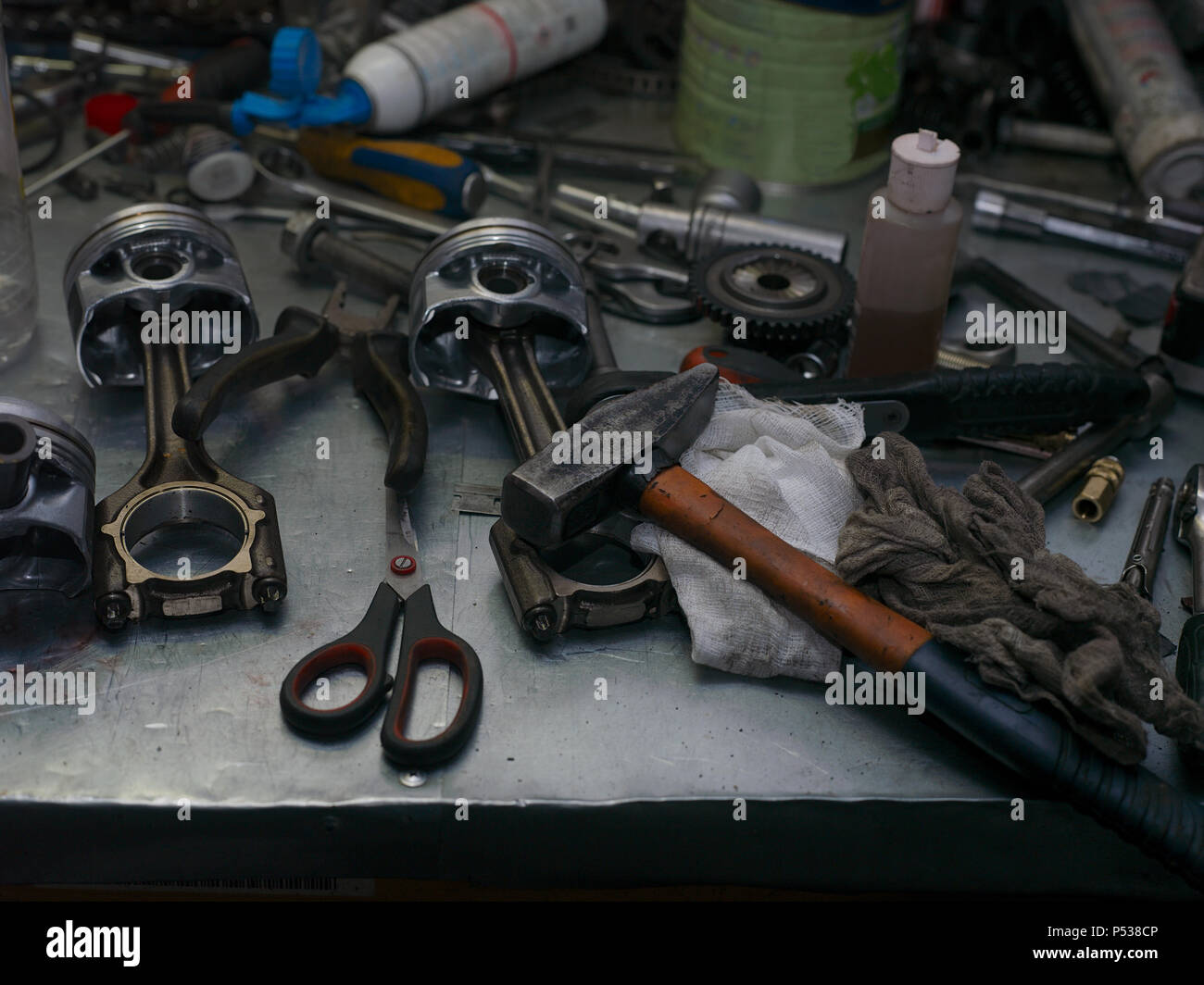 Disassembled motor spare parts and tools on a messy table in a garage ...