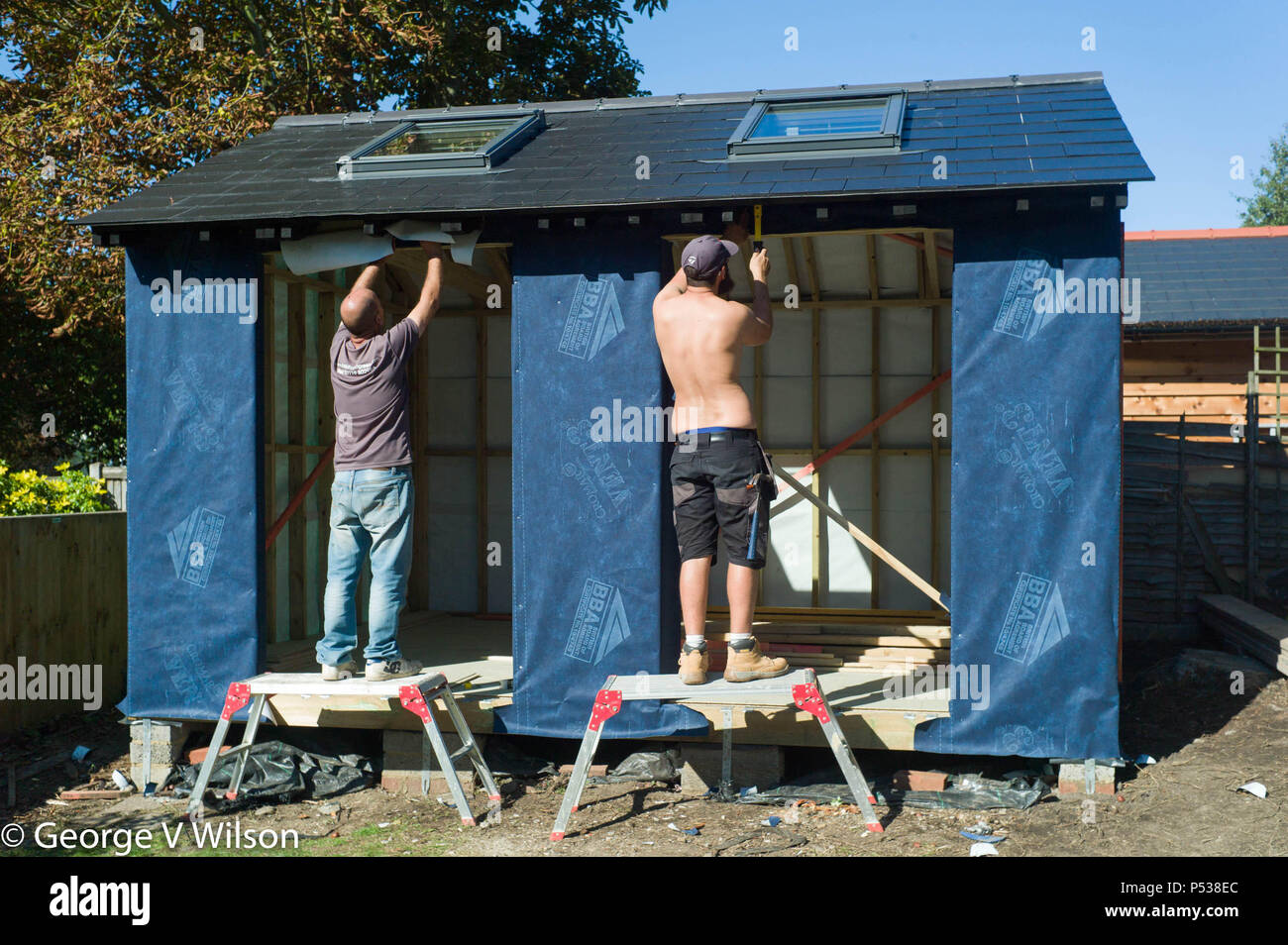 Builders constructing a large shed in a garden Stock Photo - Alamy