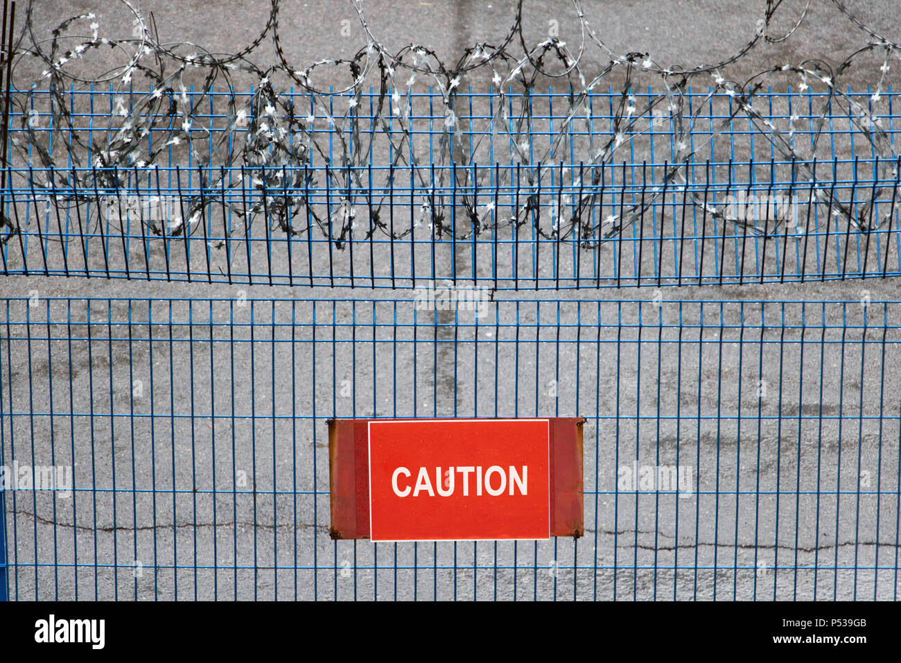 Iron fence with barbed wire. Metallic fence with red warning sign ...