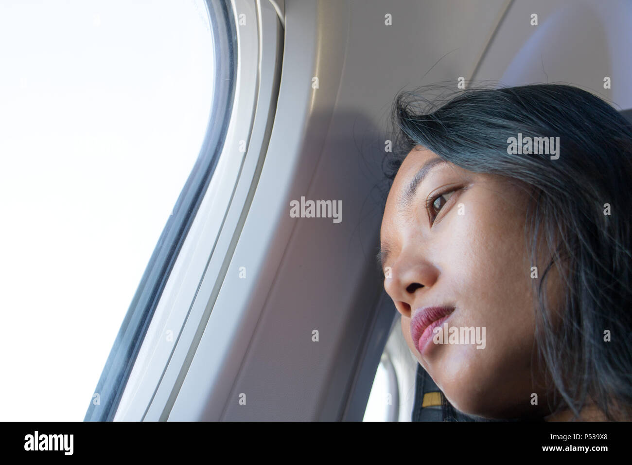 A young woman flying by plane. The passenger is looking out of the ...