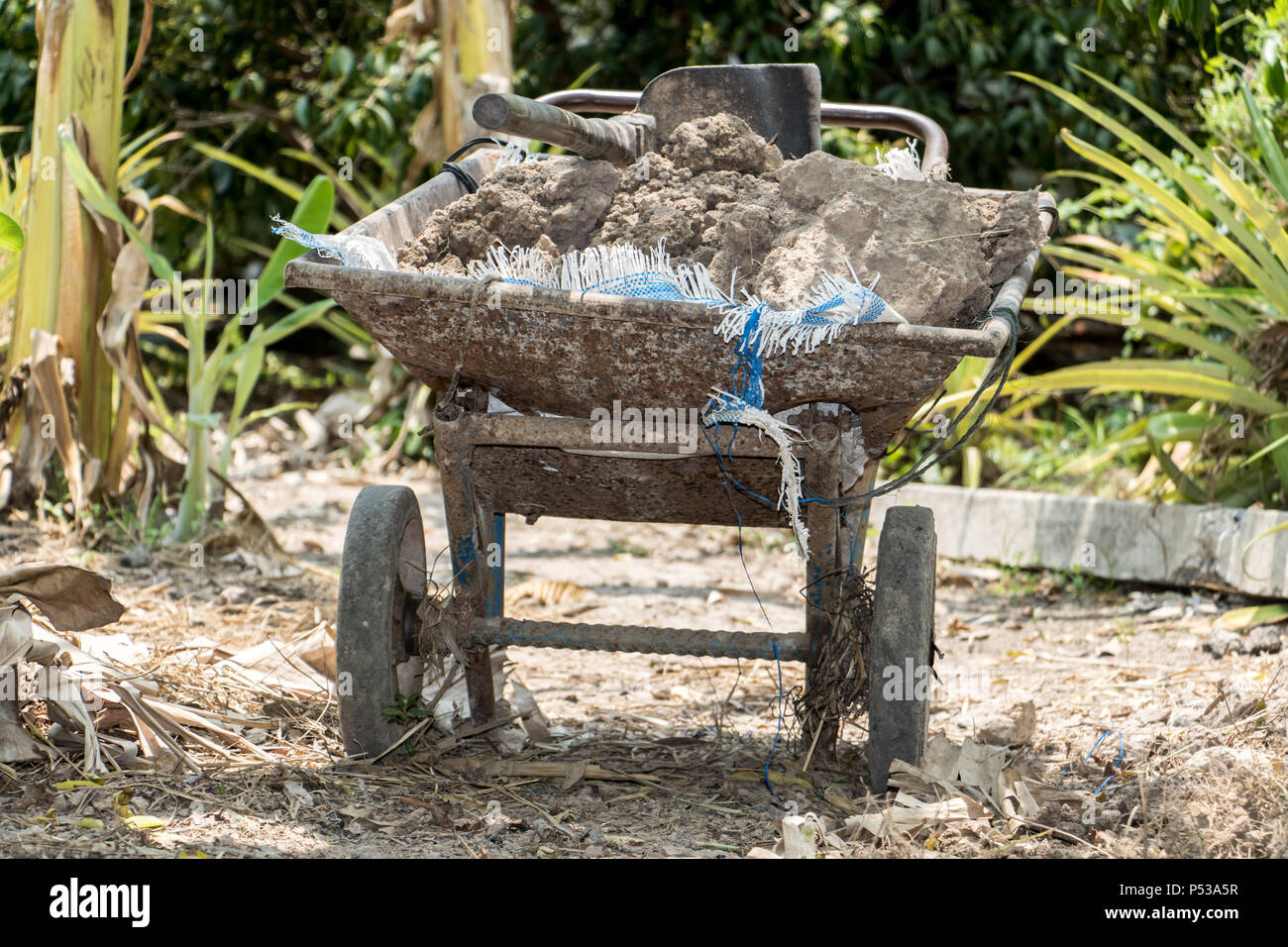 A soil with a hoe in old wheelbarrow in a tropical garden Stock Photo ...