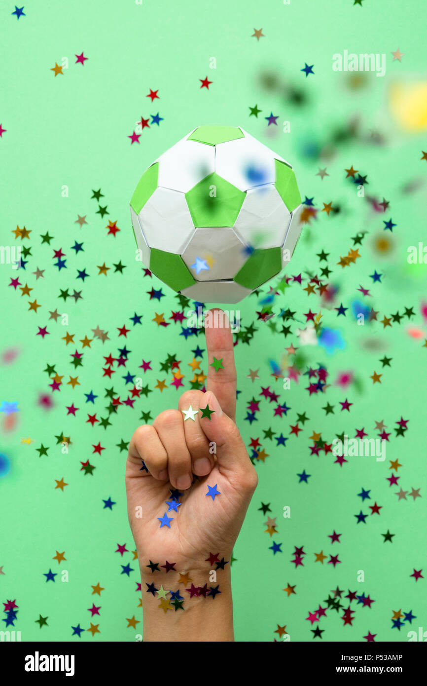 Hand spinning paper soccer ball on green background. Origami. Paper ...