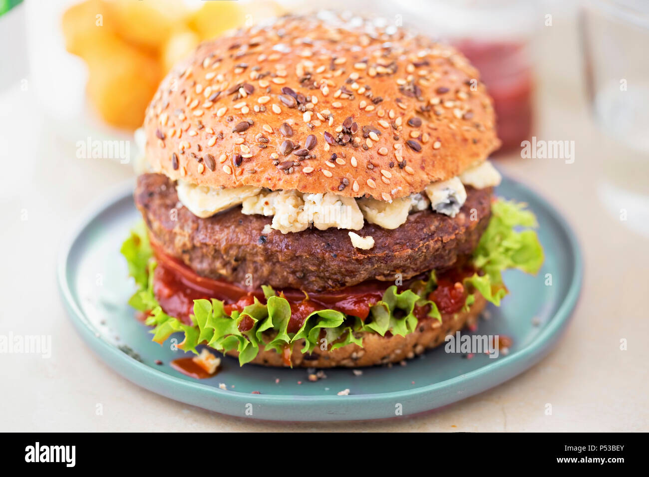 Angus burger on grain bun with tomato relish, lettuce and blue cheese ...