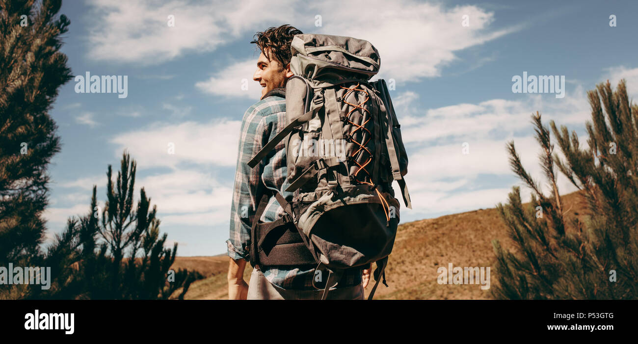 Rear view shot of happy young man with backpack going on a camping ...