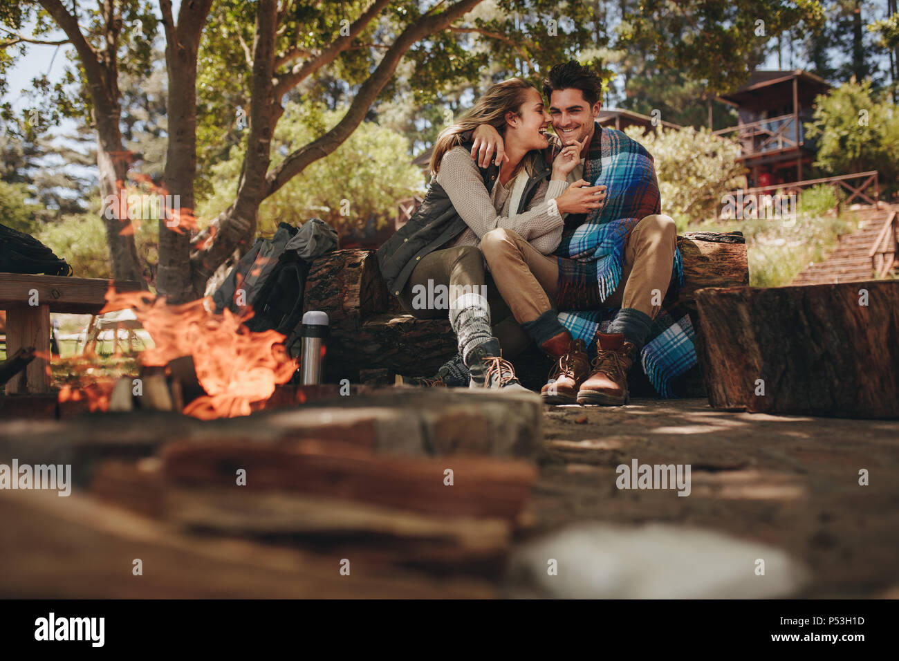 Romantic camping couple sitting by bonfire in open air. Loving man and ...