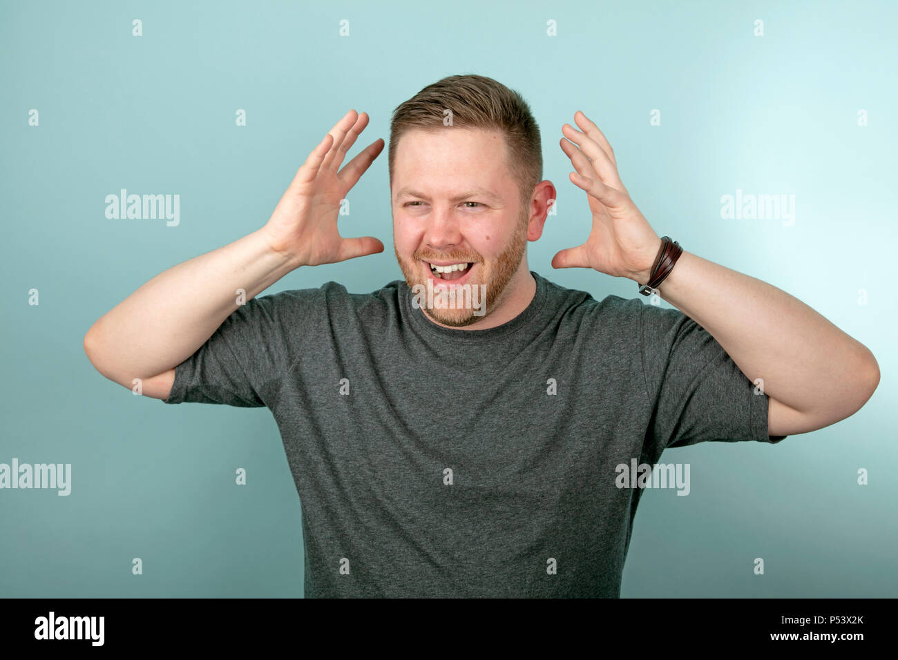 Frustrated angry man snarling and gesturing with his hands either side ...