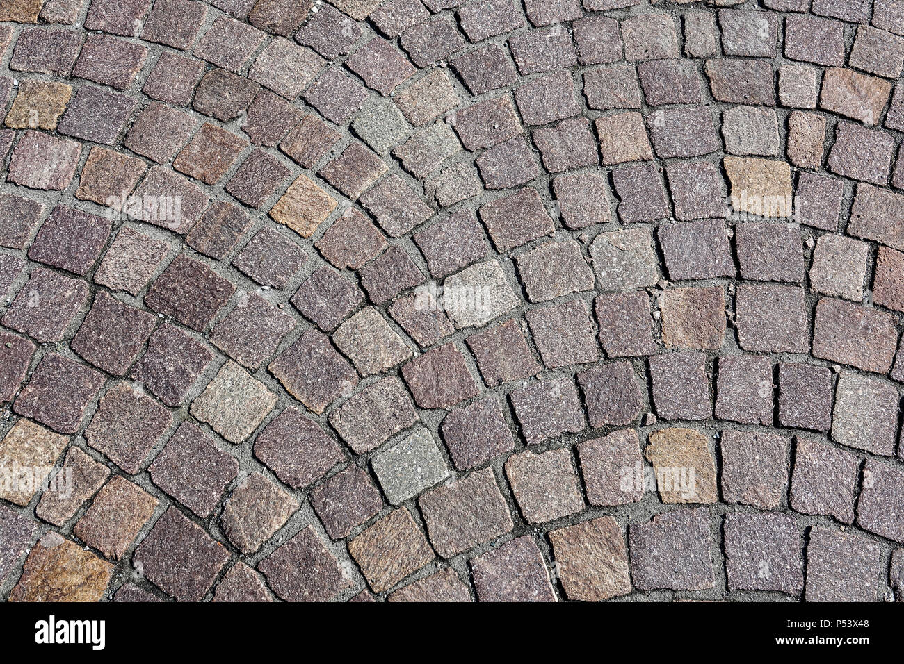Ornamental cut stone cobblestones laid outdoors in a circular pattern ...