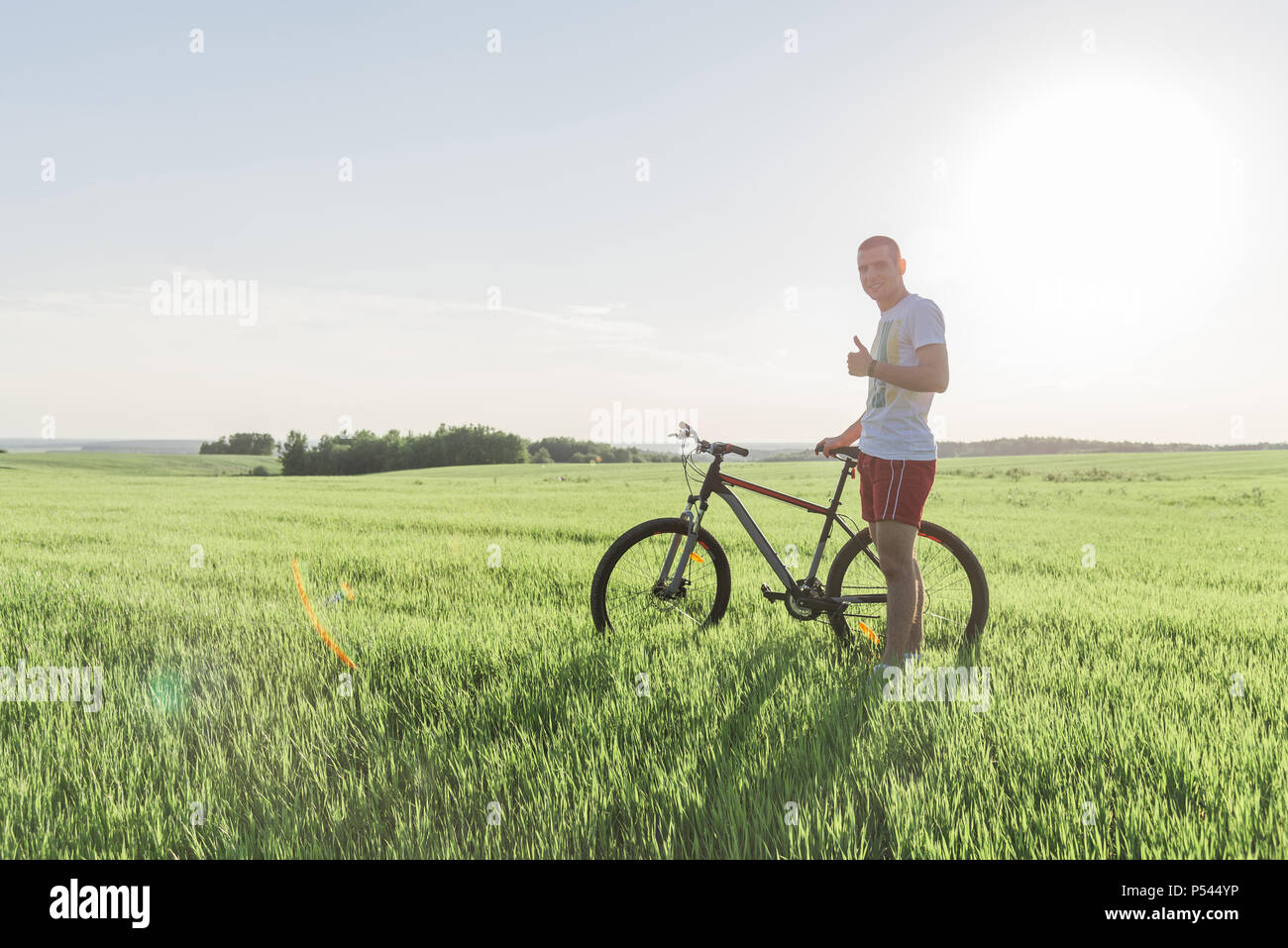 Young man standing next bike hi-res stock photography and images - Alamy