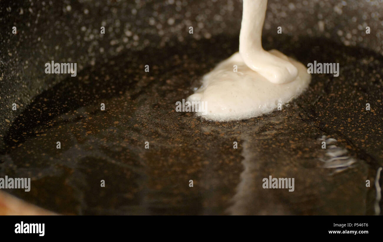 Closeup view pouring fresh white pancake dough mixture into preheat ...