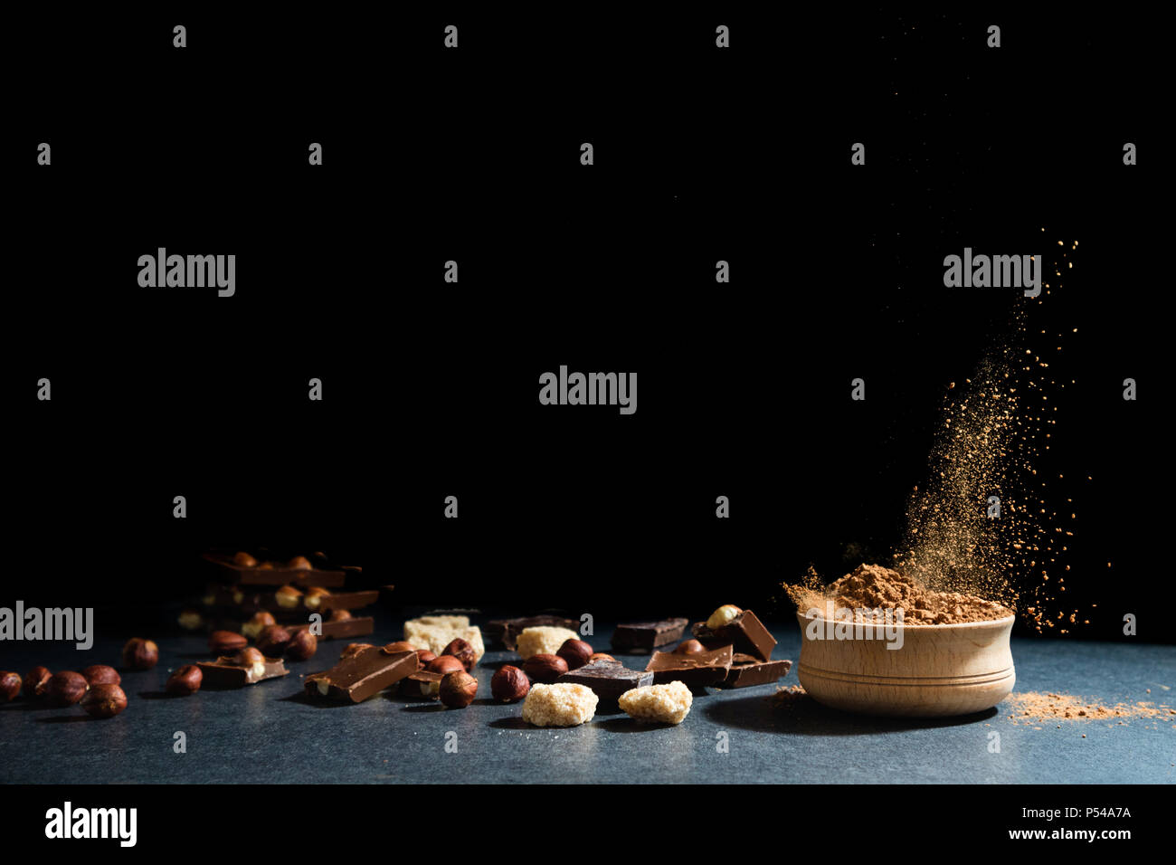 Cocoa powder in motion. Chocolate dust, cacao products, nuts on black ...