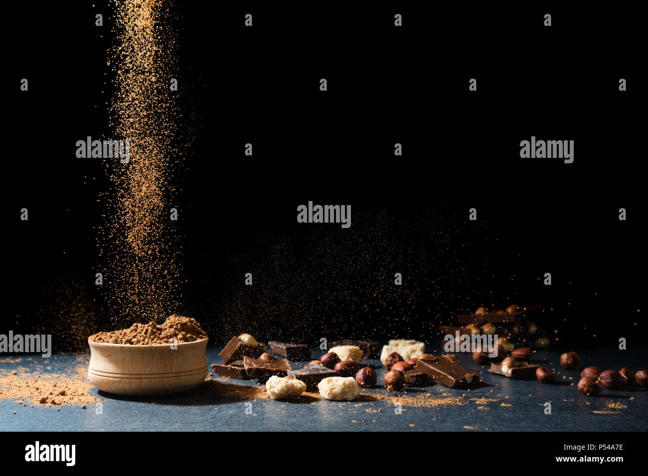 Cocoa powder in motion. Chocolate dust, cacao products, nuts on black ...