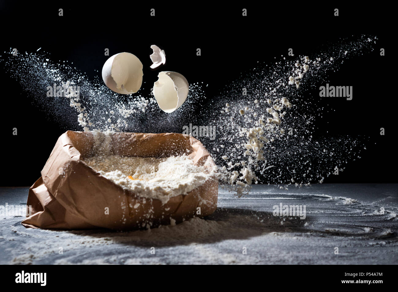 Bag with flour and egg flying in flour on black background. Flour ...