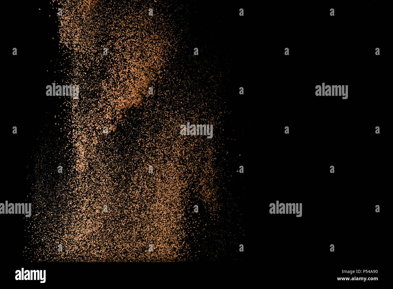 Cocoa powder sifting isolated on black background. Chocolate dust on ...