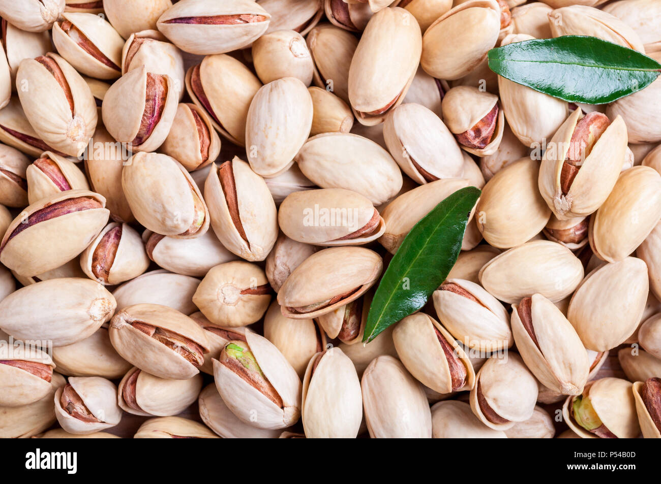 Pistachio background. Pistachio texture with leaves. Nuts. Top view ...