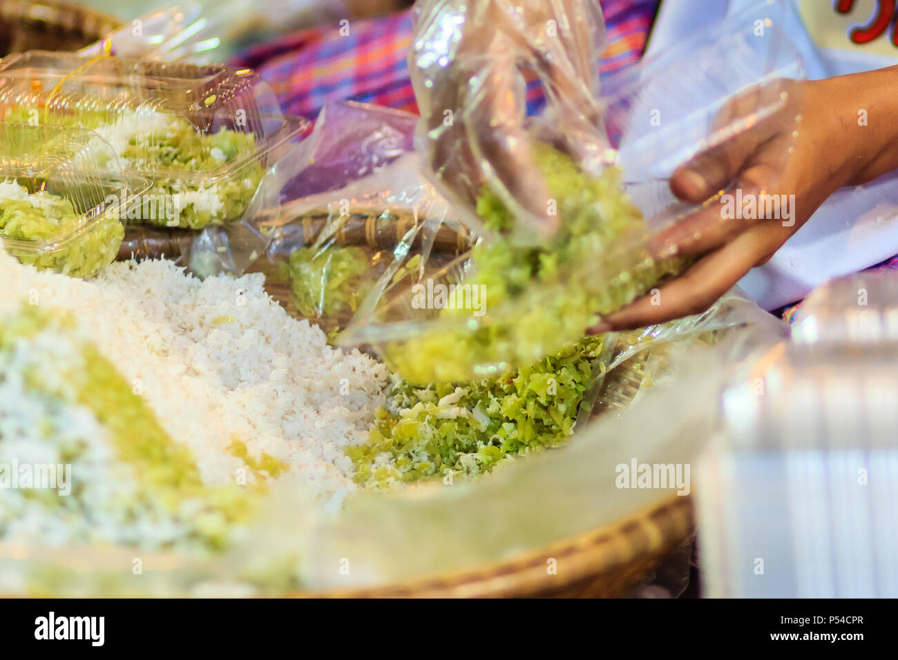 Thai vendor is selling shredded rice grain dessert to the customer at ...