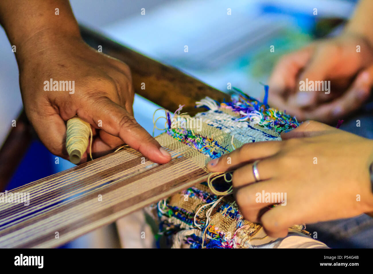 Weaver using small loom or weaving machine for weaving fabric. Weaver ...