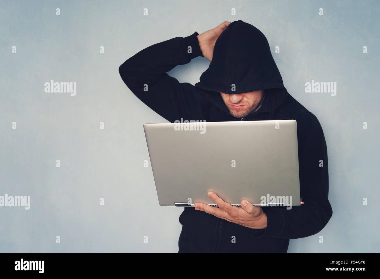 thoughtful Hacker with his computer thinking on blue background ...