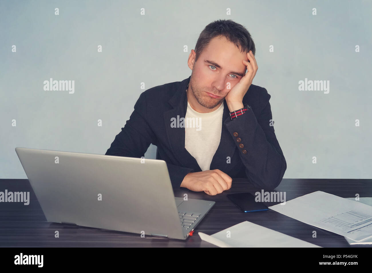 Portrait of tired male feeling headache while working with notebook ...