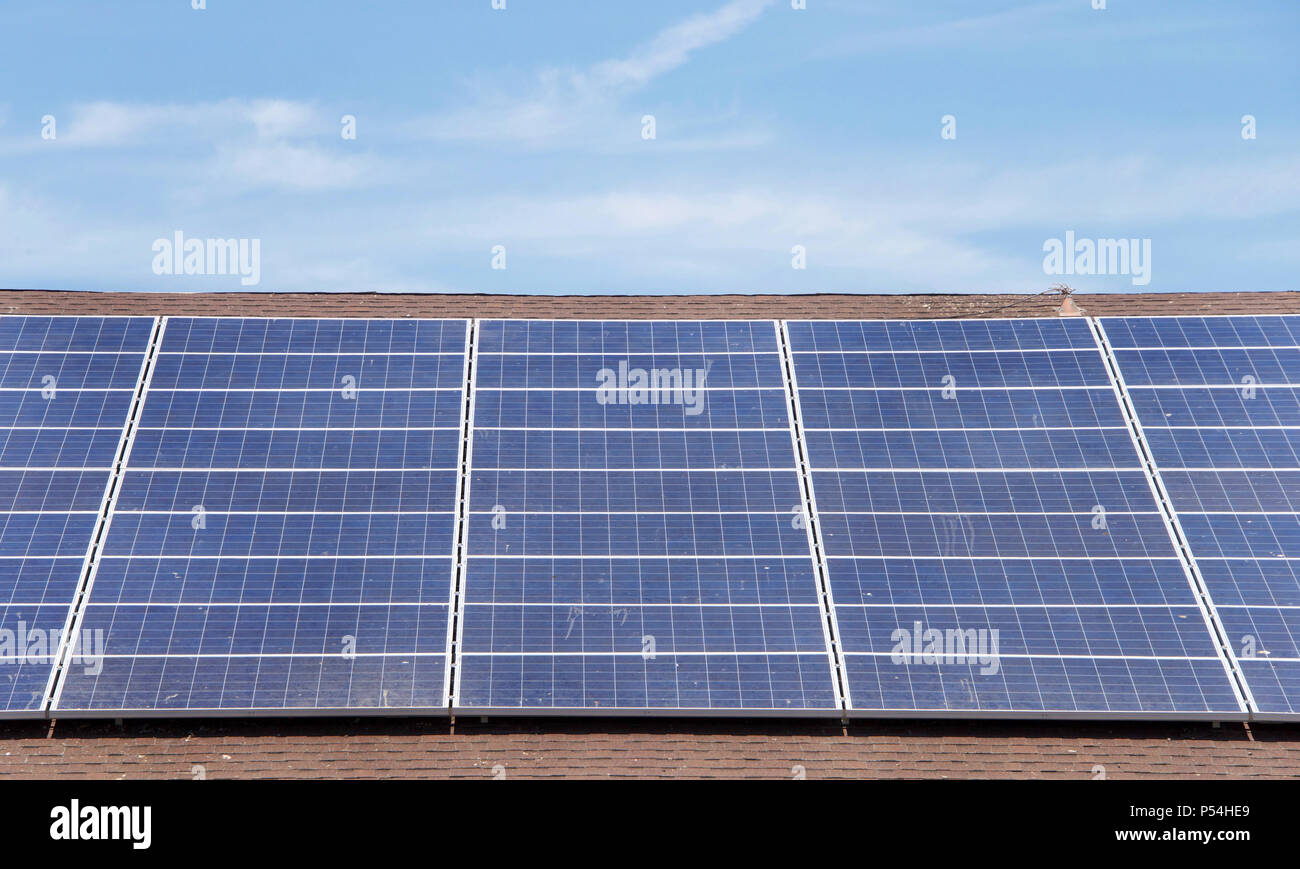 Large solar panels on a wood shingle roof, blue cloudy sky in ...