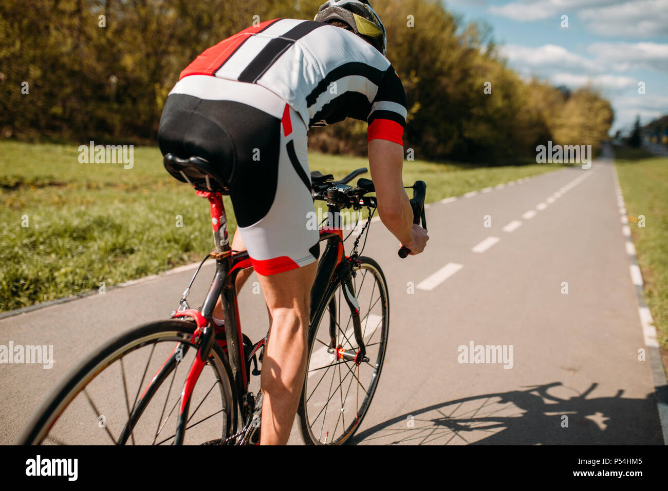 Cyclist in helmet and sportswear rides on bicycle, back view. Workout ...
