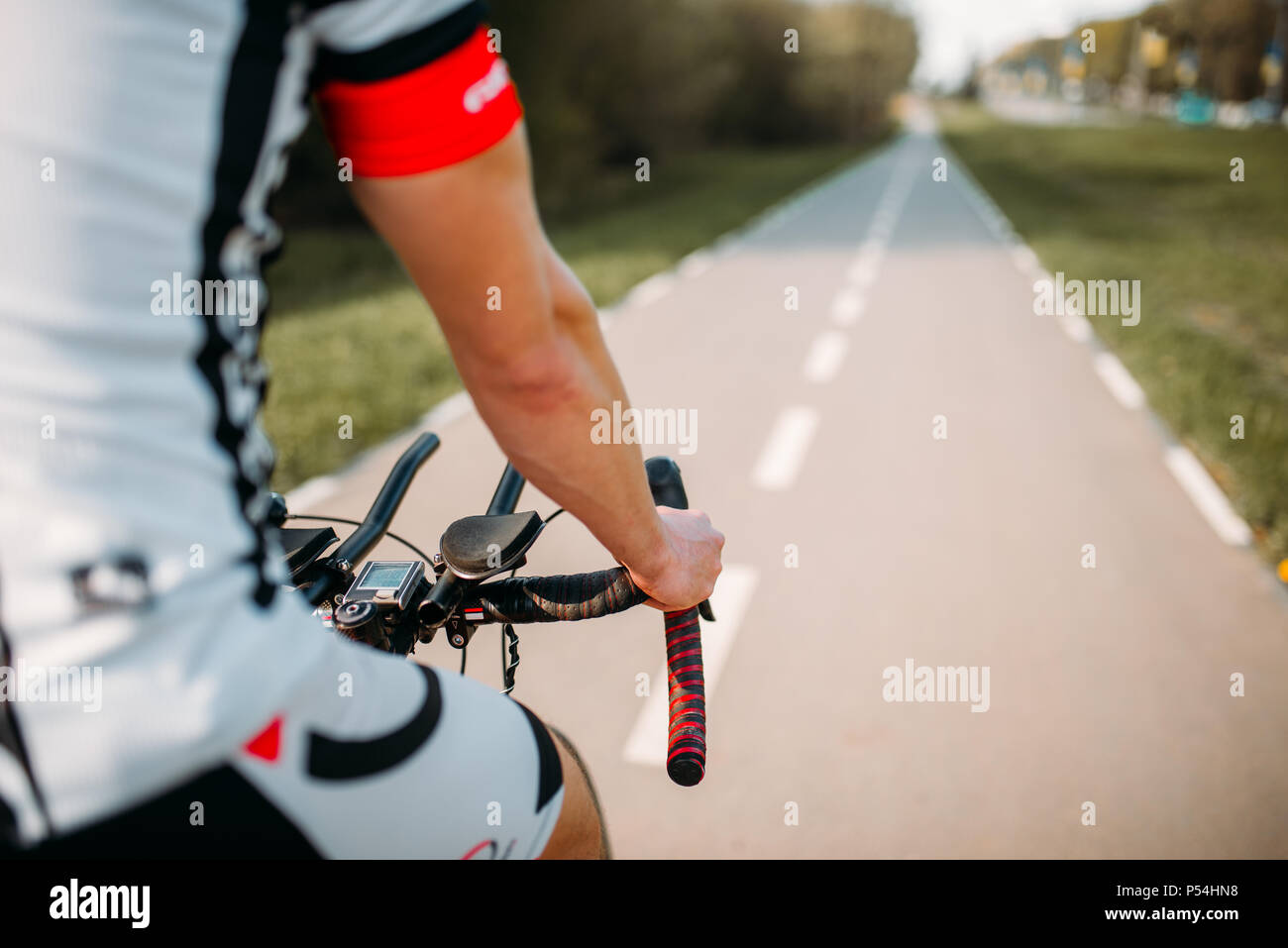 Cyclist in helmet and sportswear rides on bicycle, back view. Workout ...