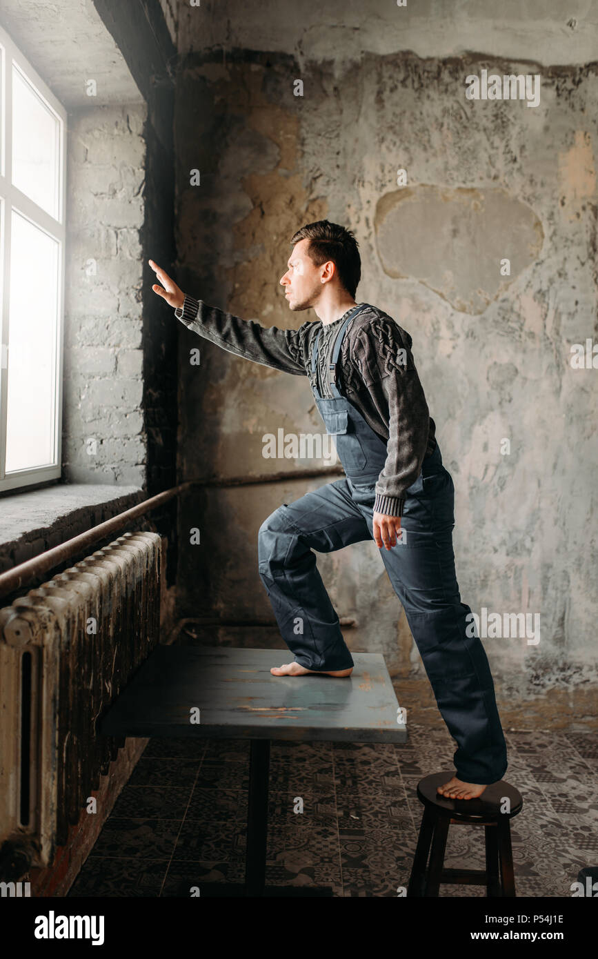 Autistic man pulls his hand to the window with light. Alone guy in ...