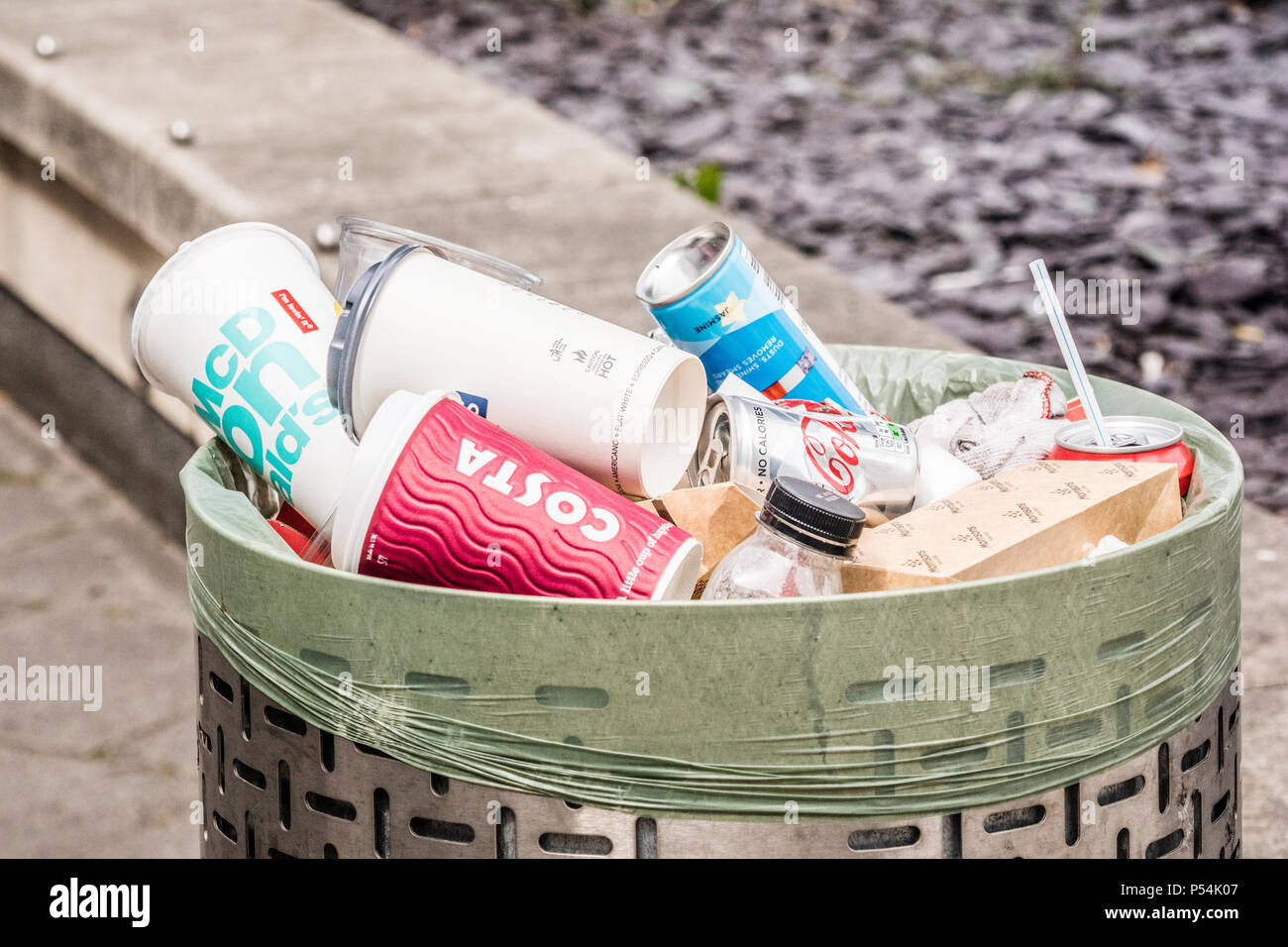 A street litter bin full of cans, plastic cups and packaging, England ...