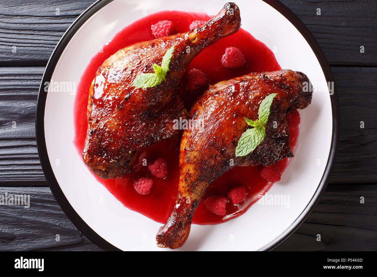 Fried duck leg with raspberry sauce decorated with mint closeup on a ...